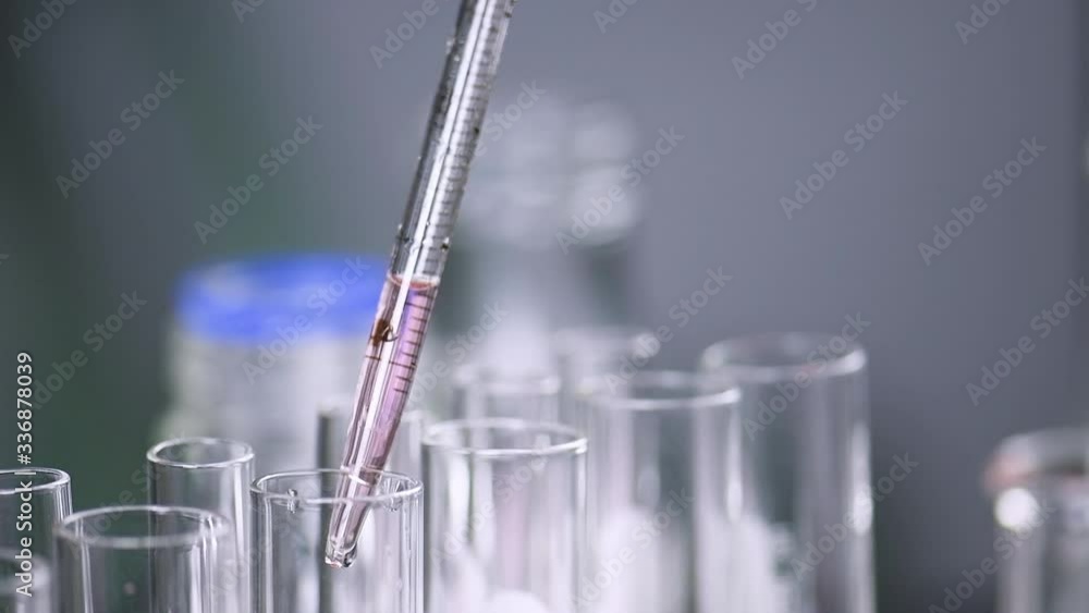 scientist hand holding a medical dropper filled with red solution ...