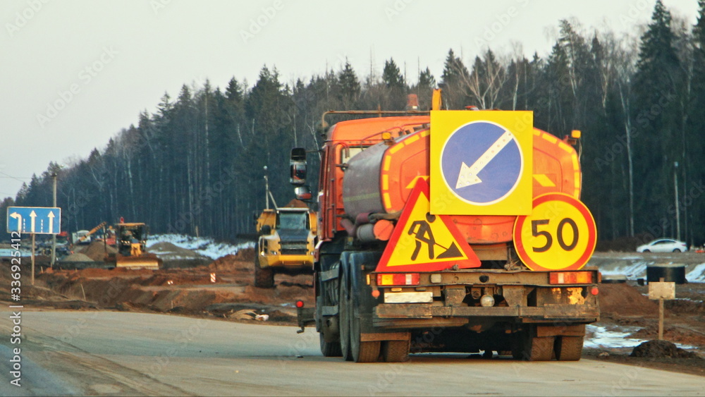 Fuel truck with orange barrel and road signs on roadside near the ...