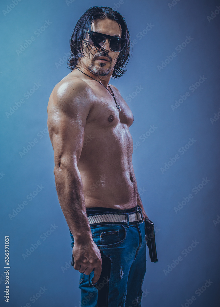 sexy muscular body model portrait of a young man holding a gun in his ...