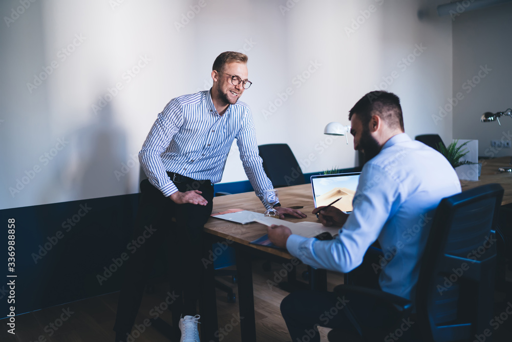 Professional male colleagues talking to each other in friendly ...