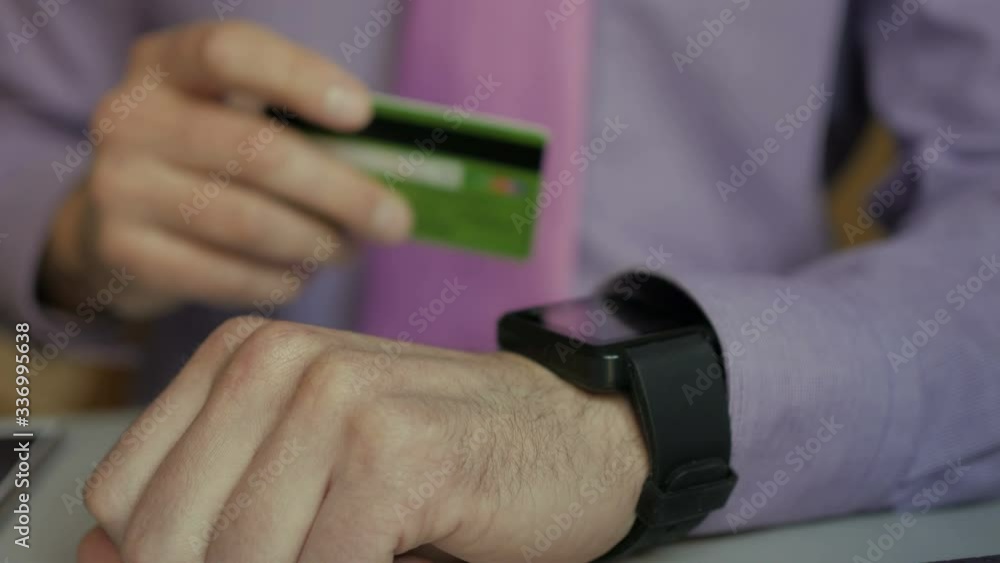 Businessman buying online with credit card on smart watch. Consumerism ...