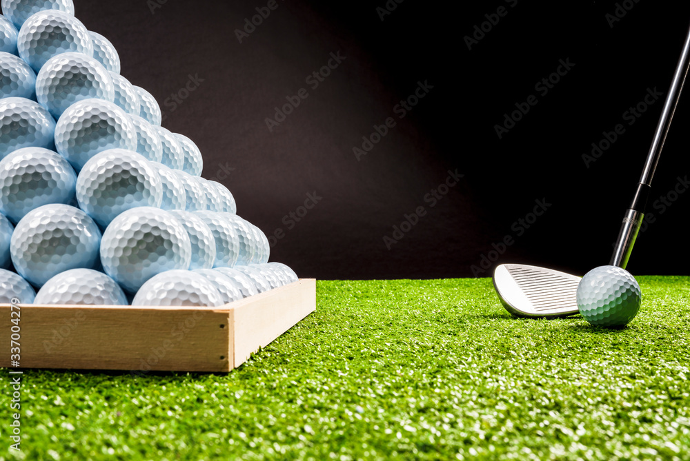 Pyramid of golf balls, golf ball and golf club in a driving range ...