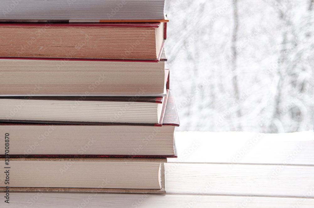 Book stack on wood desk and blurred bookshelf in the library room ...