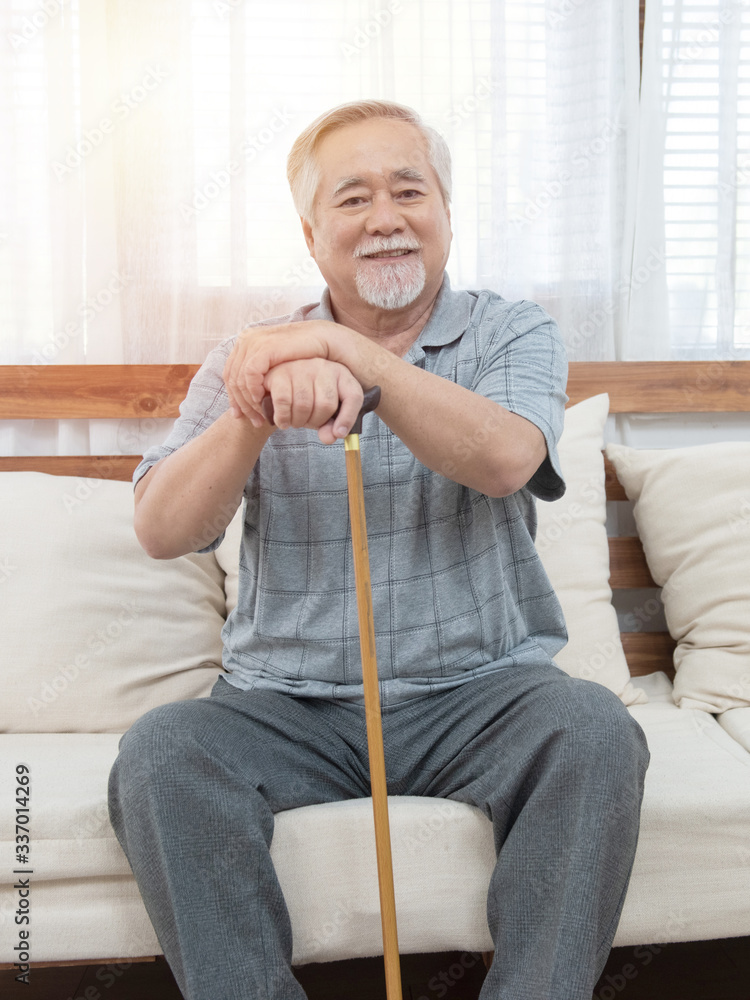 elderly old senior man sitting, resting his hands on wooden walking ...