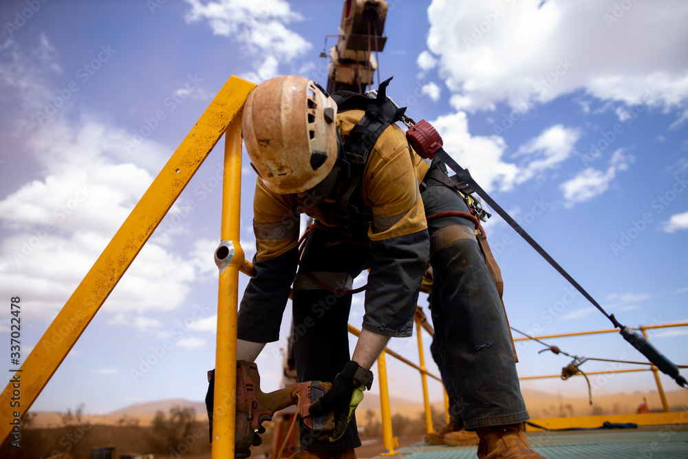 Trained worker wearing working at heights safety harness helmet ...