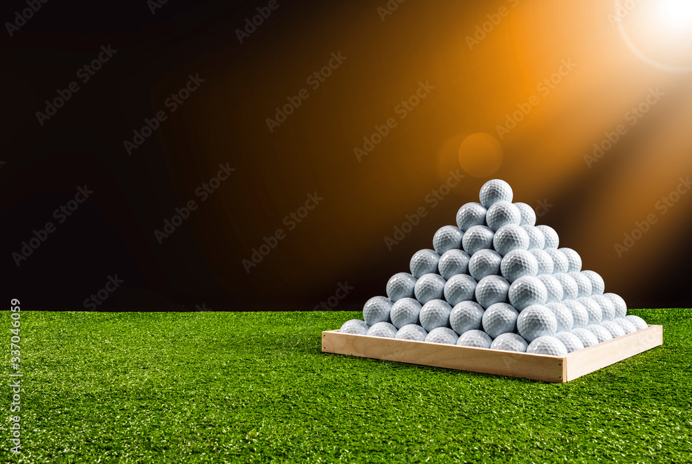 Pyramid of golf balls in a driving range with orange light glow ...