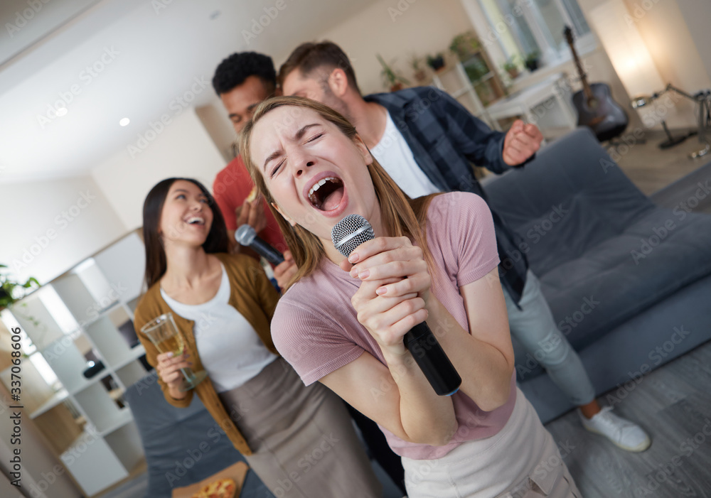Karaoke singer. Beautiful young girl holding microphone and singing while playing karaoke with ...