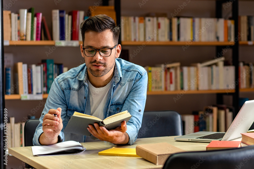 Foto de Young male student study in the library reading book. do Stock ...