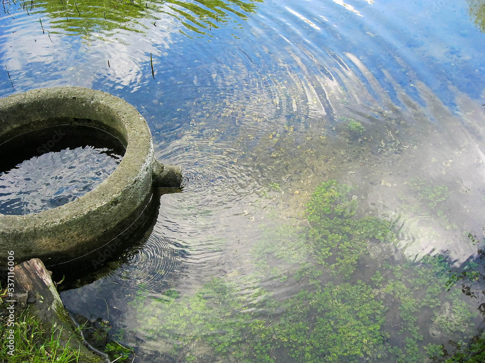 Concrete springlet with wooden path in small river surrounded by ...