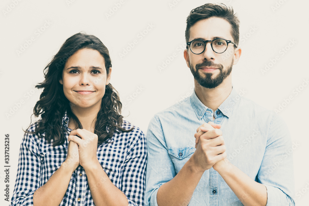 Excited couple hoping for luck, making prayer gesture. Young woman in ...