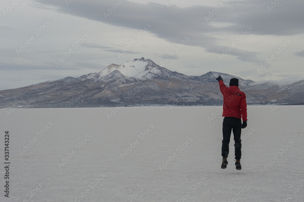 man jumping and pointing his hand towards the volcano crater on the ...