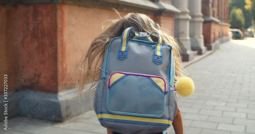 Follow up shot of little girl running into school building. Backside ...