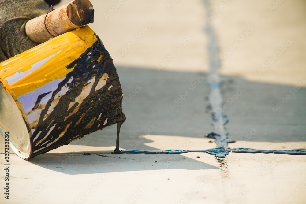 Worker sealing asphaltic joint for construction joint on concrete ...