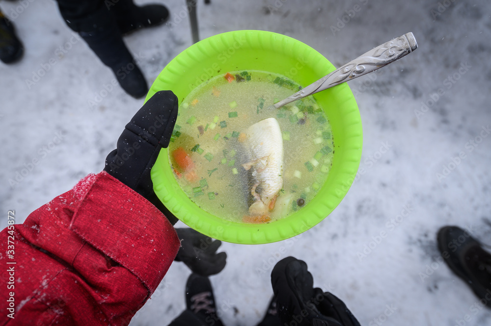 Tourist holding a hot of Omul fish soup in hand during picnic in lake ...