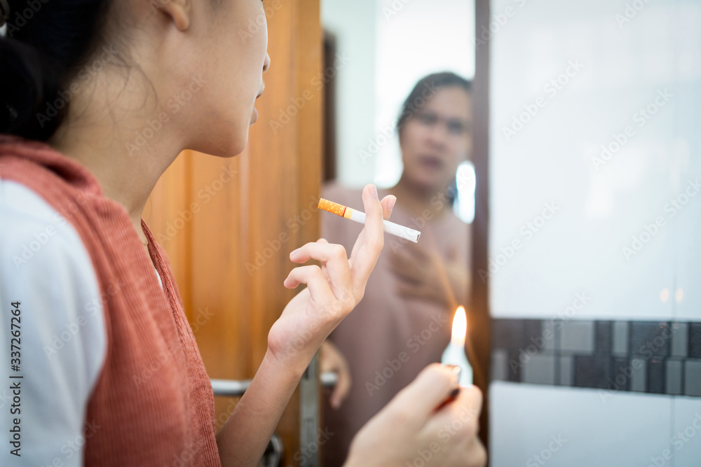Teenager girl light up the cigarette at home,woman secretly smoking the ...