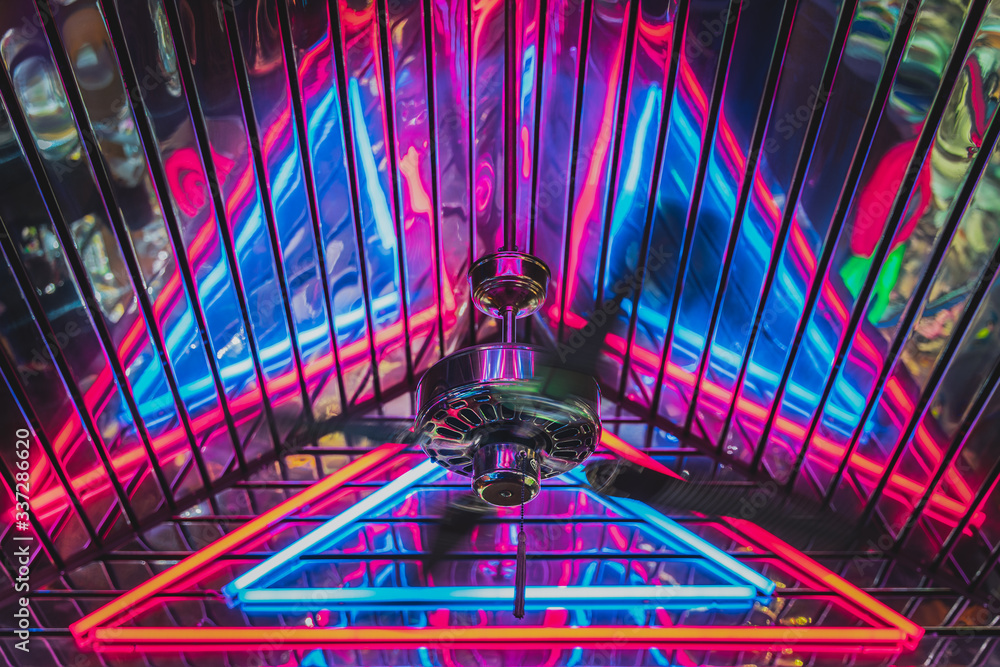 Double neon triangle two time reflected with a fan spinning in the ...