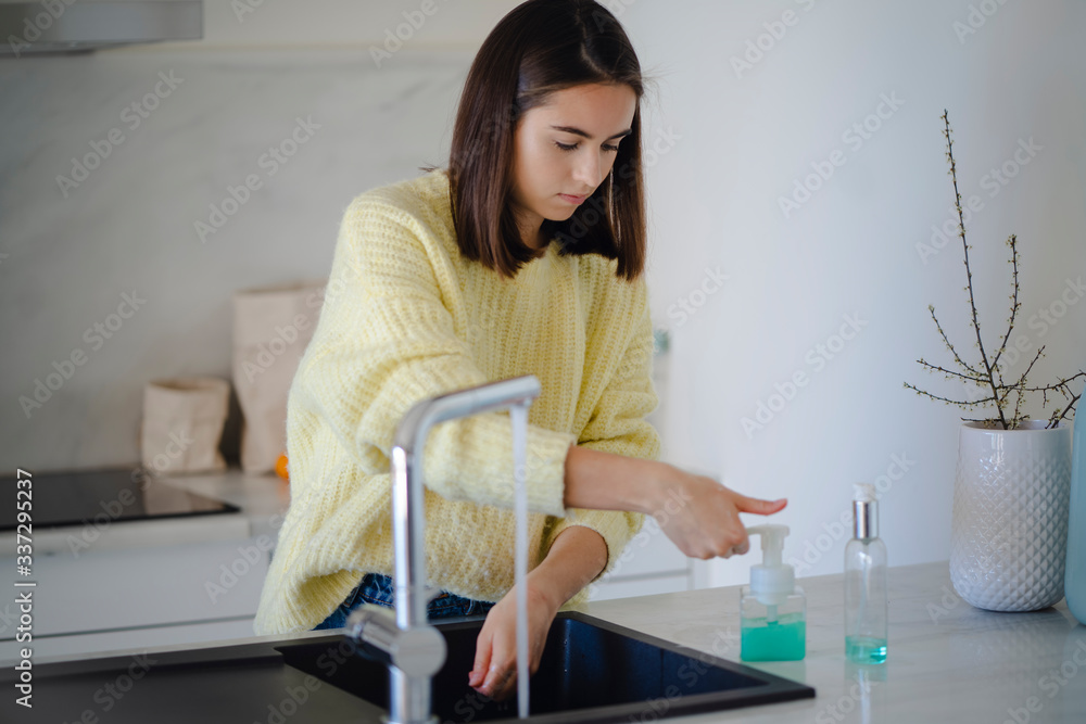 Young pretty girl washing hands with soap on her kitchen during the ...
