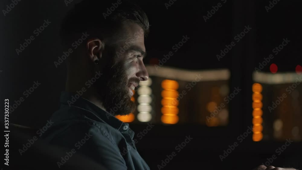A close-up side view of a laughing handsome young man is using his ...