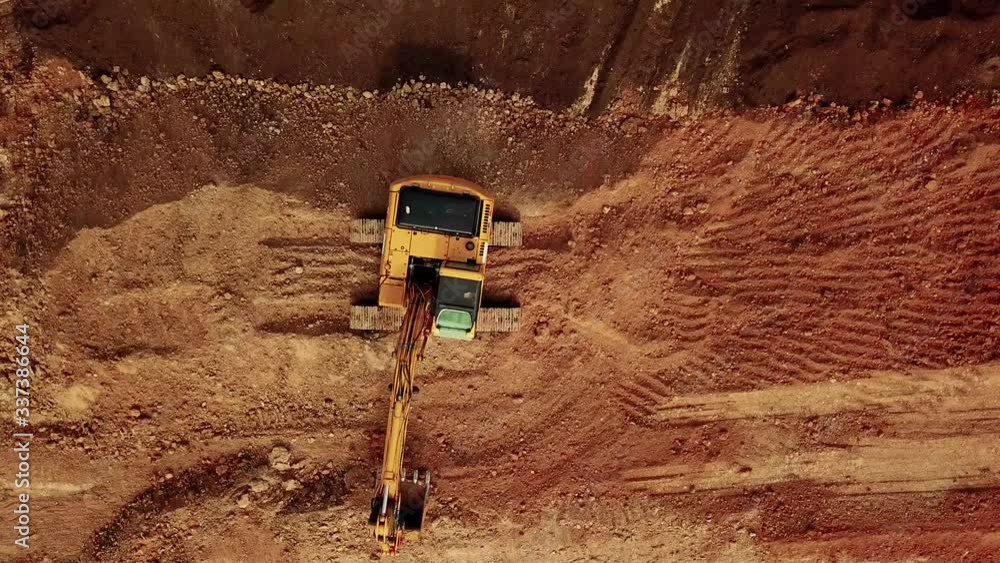 Drone vertical, fixed position wide shot of yellow excavator crane with ...