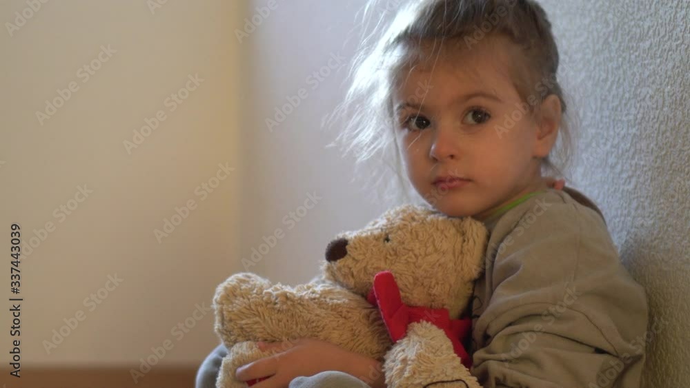 Abandoned child. Little girl beside the wall by the window alone with ...