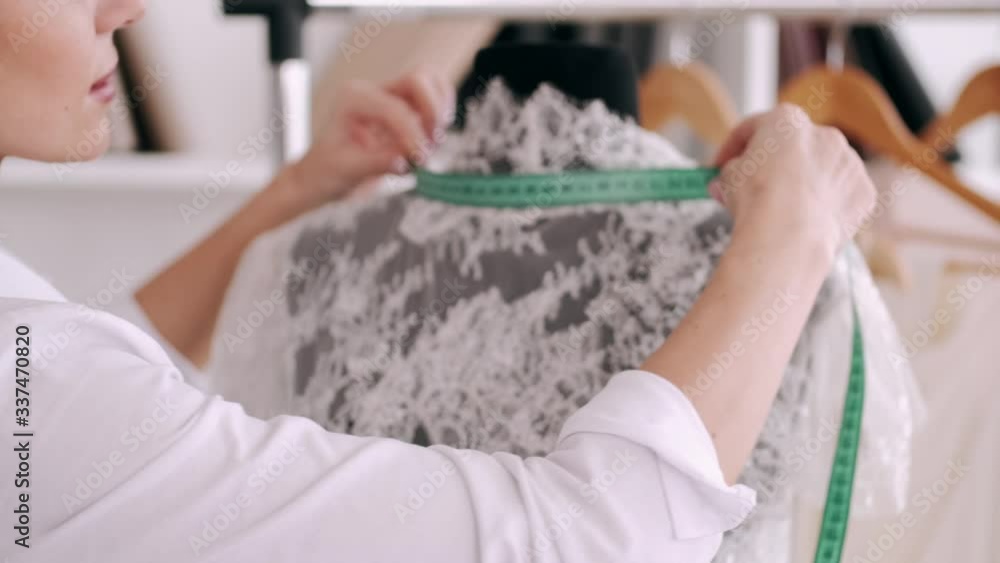 Beautiful female tailor is measuring a model of a lovely dress. The ...