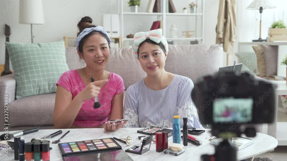 Two beautiful asian woman blogger showing applying makeup on face ...