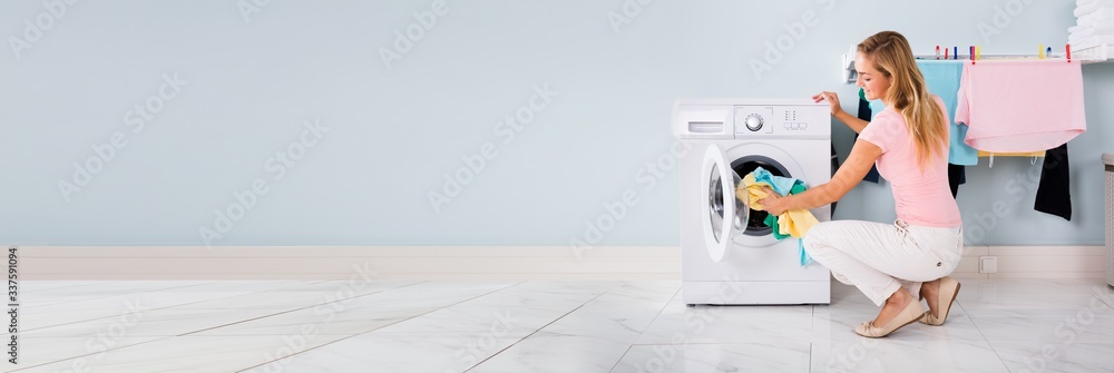 Woman Putting Clothes In Washing Machine Stock Photo | Adobe Stock