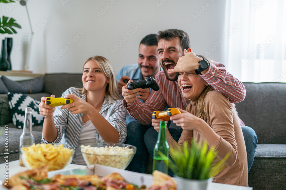 Happy friends playing video games at home. Stock Photo | Adobe Stock