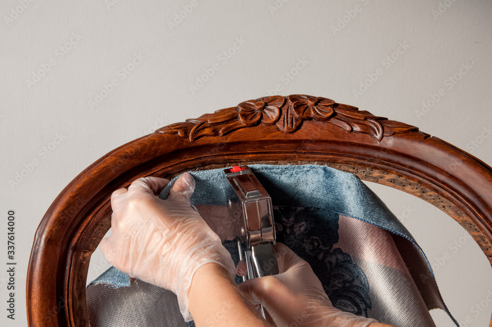 using a stapler for upholstering the trim to the backrest of an old ...