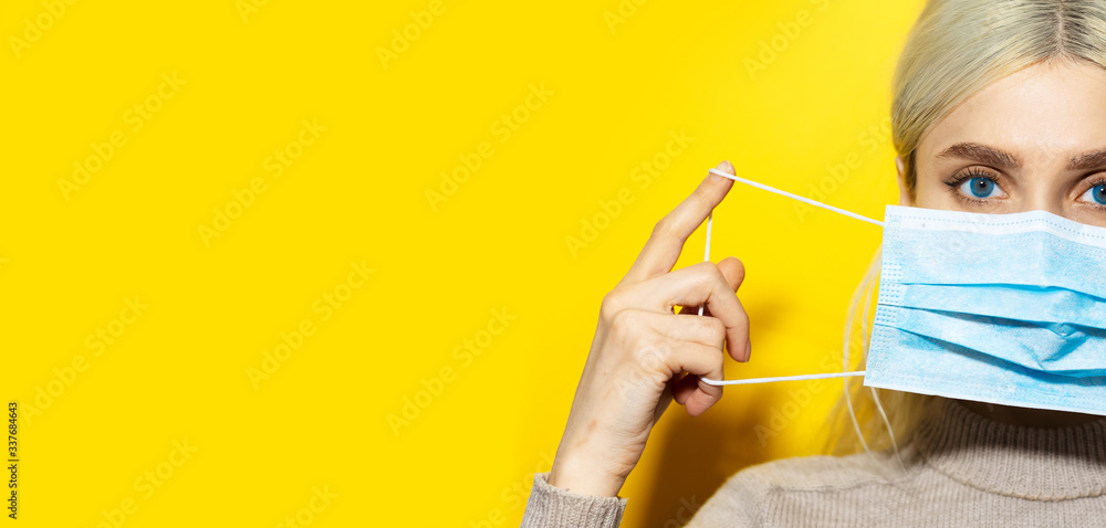 Half face portrait of young blonde girl with blue eyes putting on ...