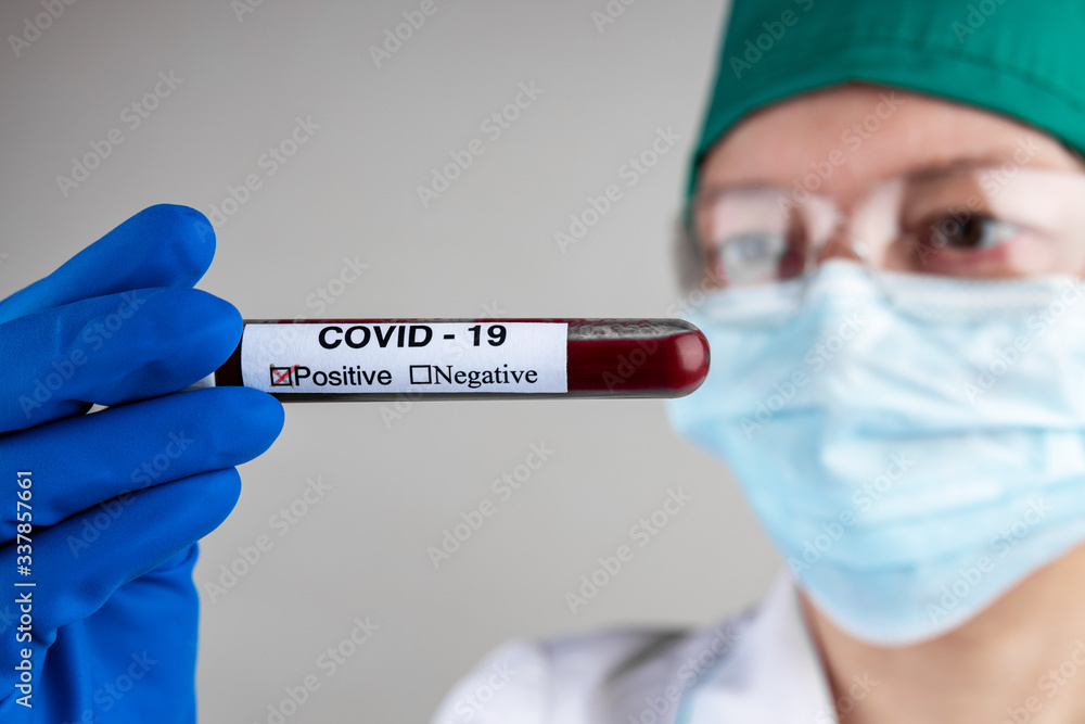 Coronavirus epidemic, a nurse in a respiratory mask holds a test tube ...