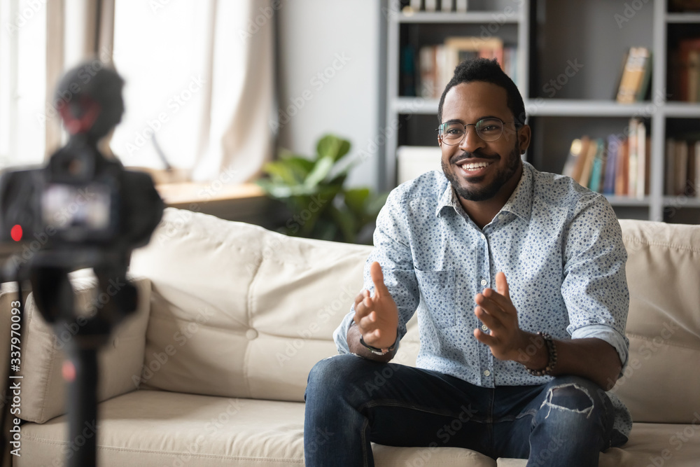 Happy young african american man speaker in eyewear sitting in front of ...