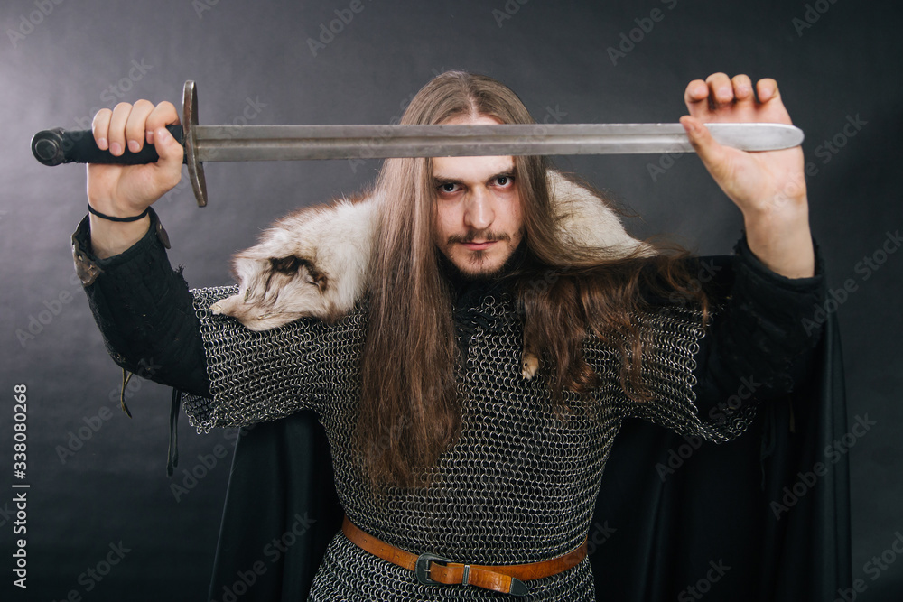 Warrior in chain mail and with a sword in a black cloak. Handsome guy ...
