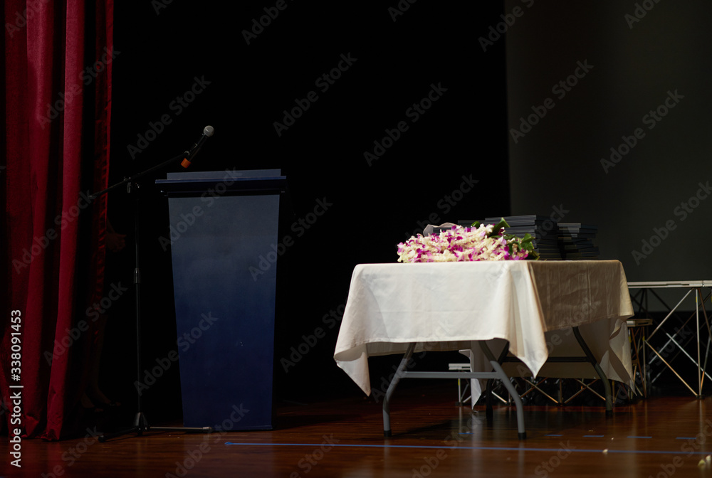 Fotka „podium at graduated ceremony with table of congratulation flower ...