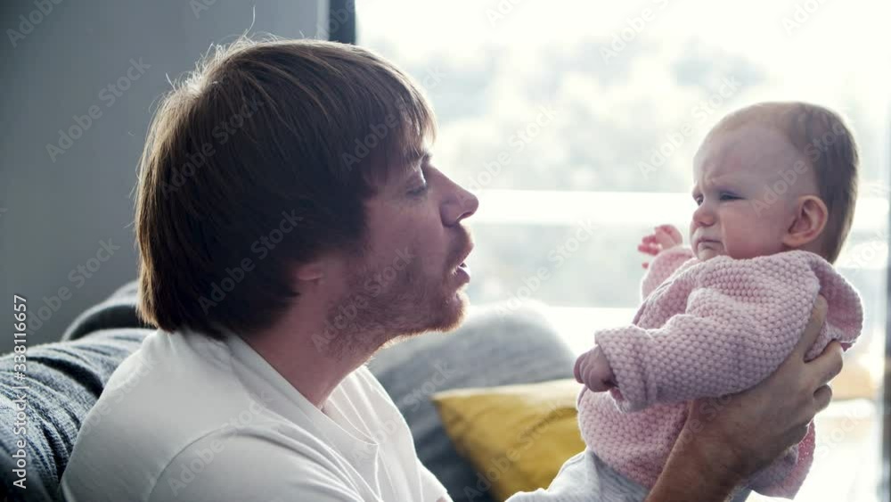 Happy dad holding and raising baby daughter. New father nursing little ...