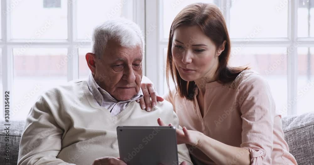 Grownup granddaughter teaching older grandpa using digital tablet, two ...