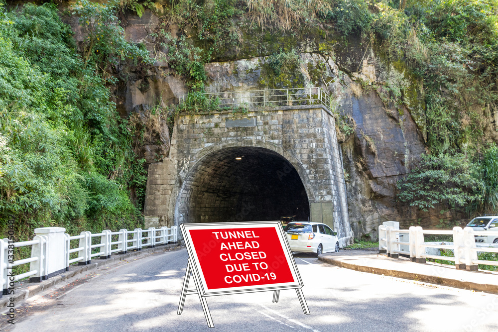 ''Tunnel ahead closed due to COVID-19'' road sign stand against a ...