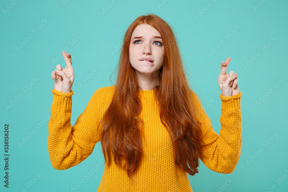 Young redhead girl in yellow sweater isolated on blue turquoise ...