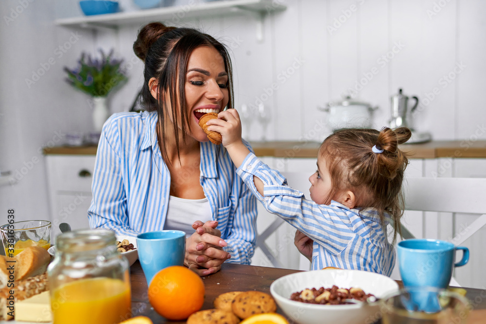 Mom and daughter have breakfast in the morning at home. They eat cereal ...