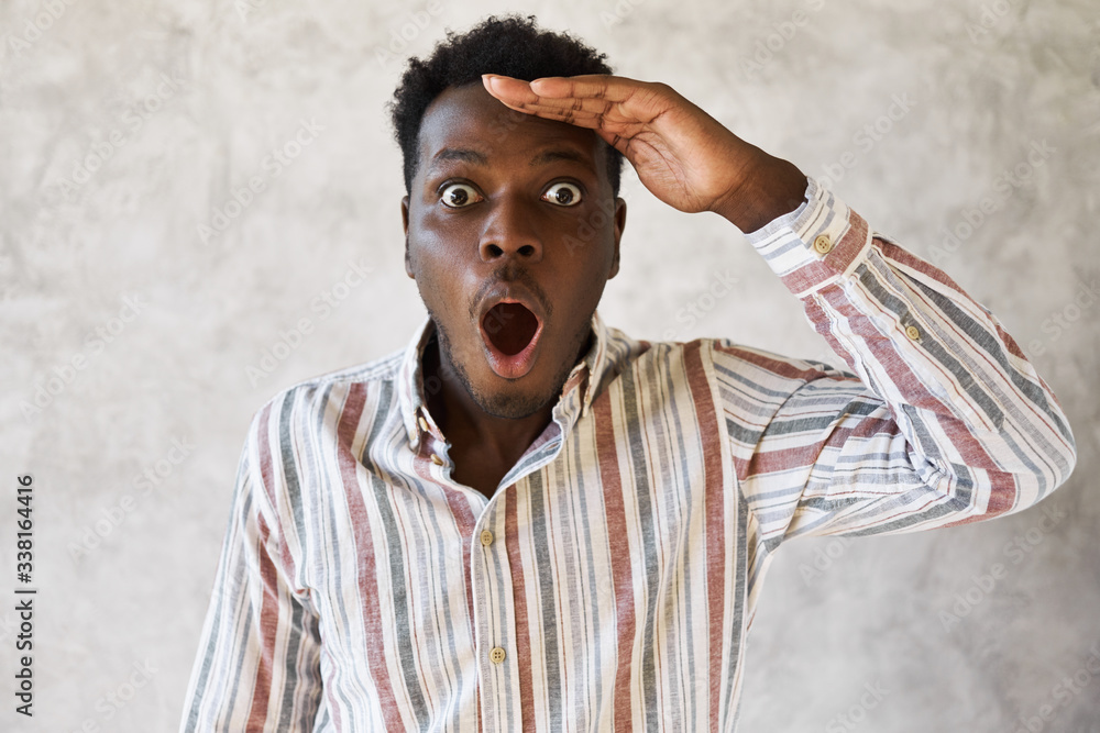 Funny nosy young dark skinned guy posing in studio with jaw dropped ...