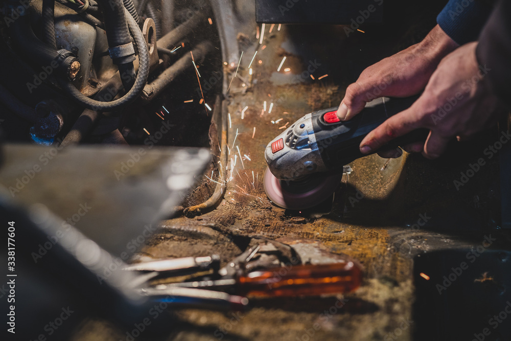Bare hands of a man using an angle grinder to cut off the excess rusty ...