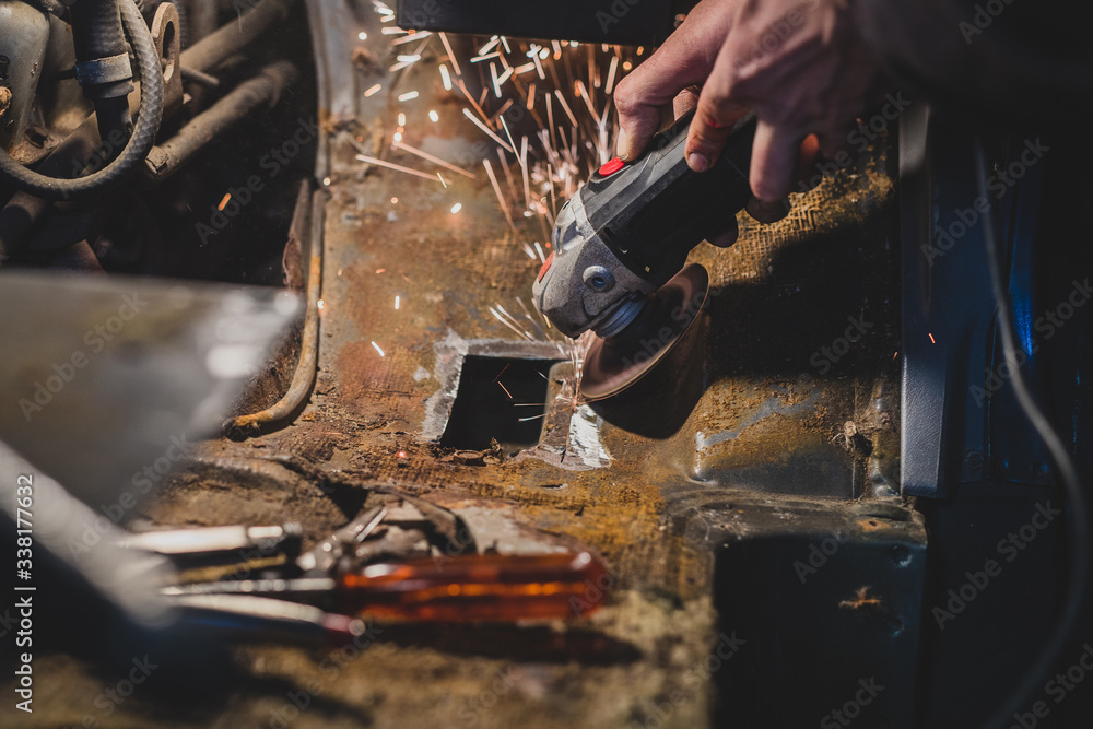 Bare hands of a man using an angle grinder to cut off the excess rusty ...