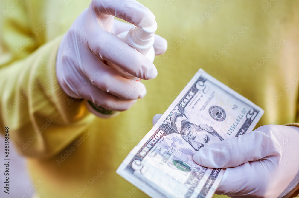 Disinfection of money. Hands in white medical gloves are spraying ...