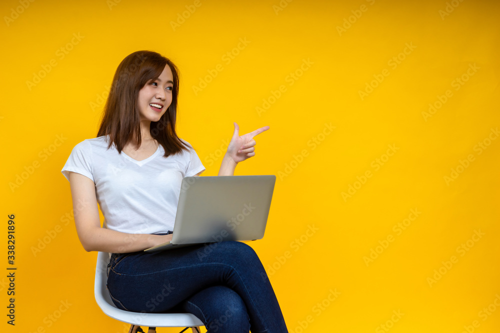 Young Asian woman smiling sitting crossed legs on chair with laptop ...