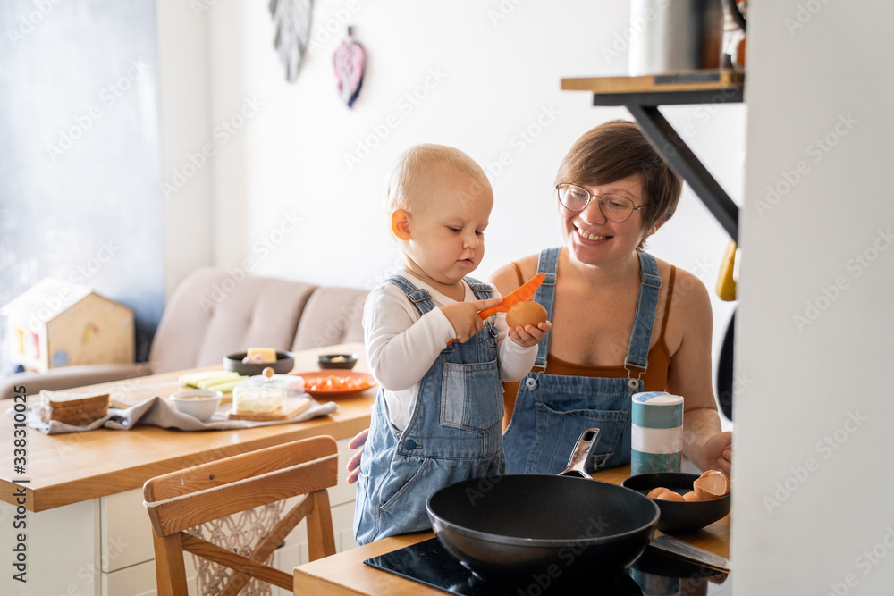 A child in the kitchen with his mother prepares breakfast, breaking an ...