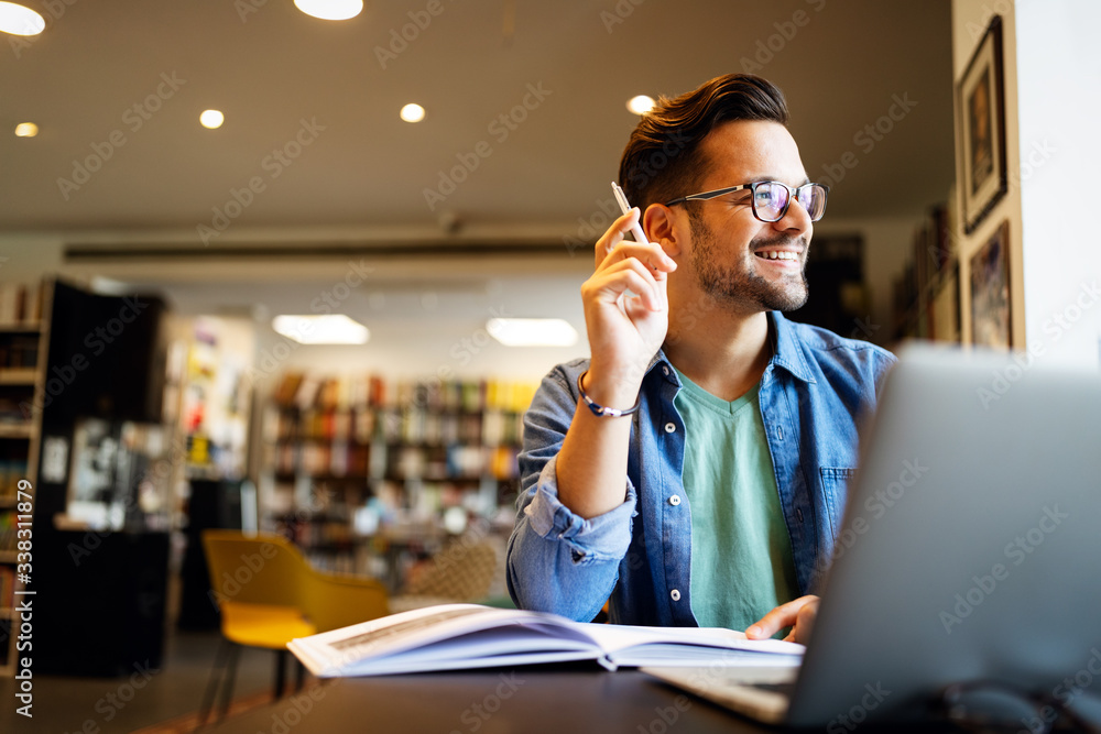 Young man student with laptop studying in the university library Stock ...