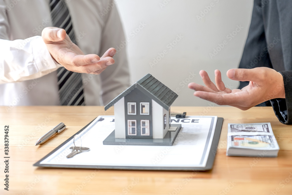 A real estate agent with House model is talking to clients about buying ...