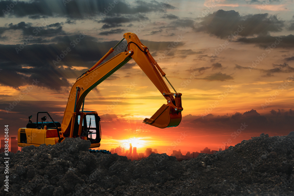 Excavators are digging the soil in the construction site on the sunset ...