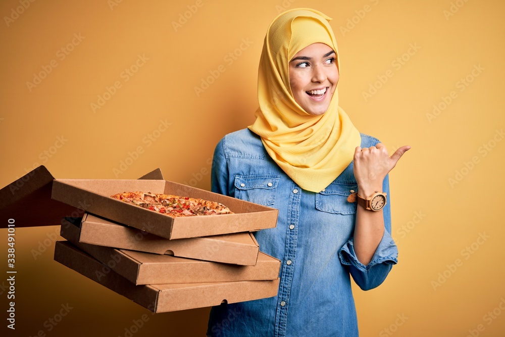 Young girl wearing muslim hijab holding boxes with Italian pizza over ...