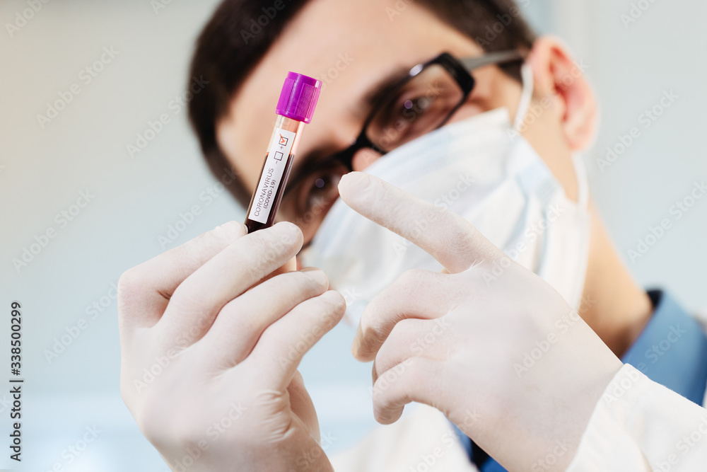 A virologist doctor is examining a sample of a blood test with ...
